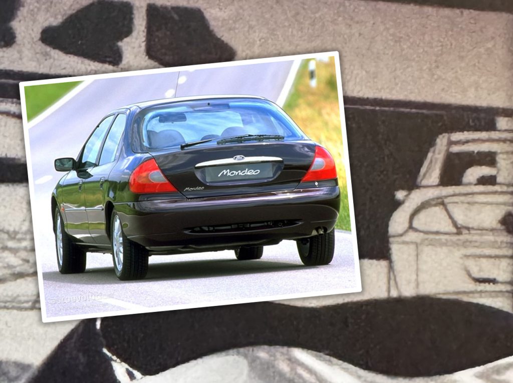 What The Hell Is This Mid-Engined Sedan On The Wall Behind A Prototype ...